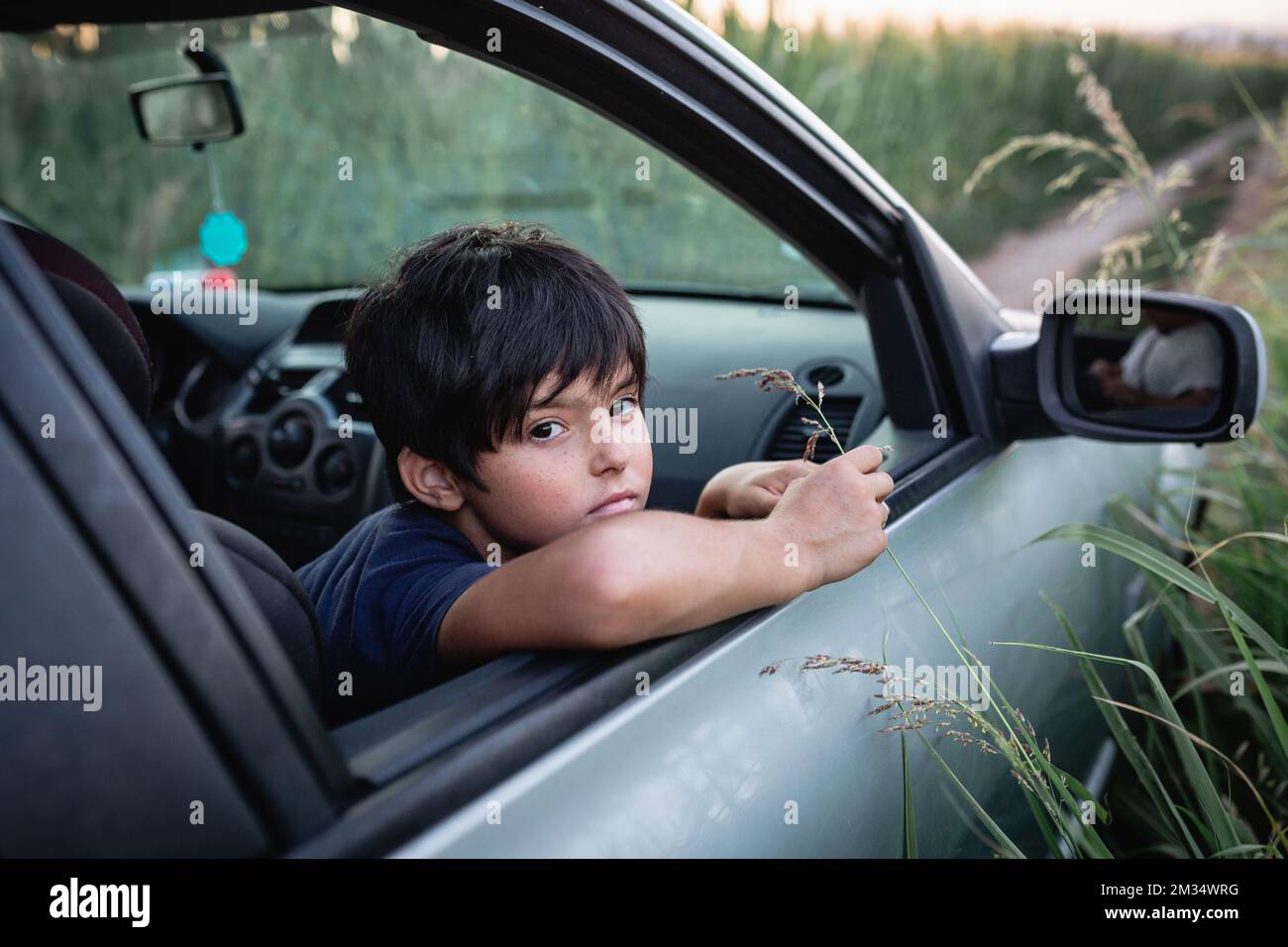 thoughtful girl with short dark har watching from family car windows ...