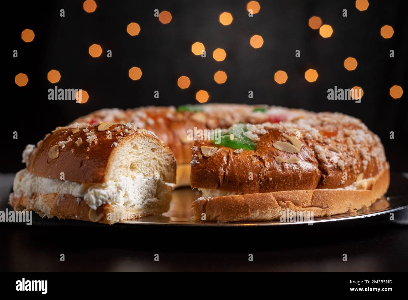 Roscon de reyes or king cake with a cut piece revealing the cream ...