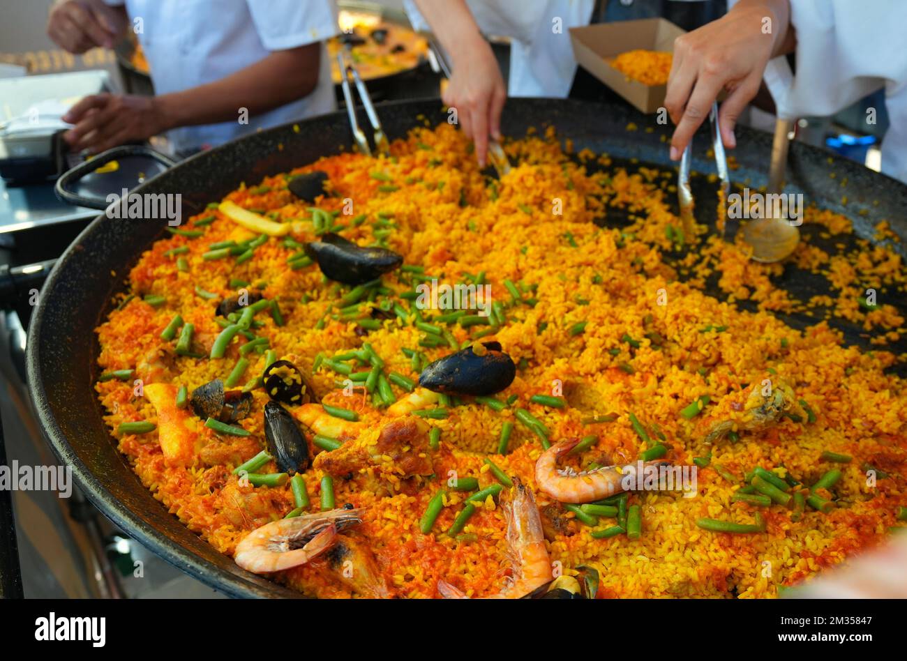 A close-up shot of people cooking paella in a street market Stock Photo ...