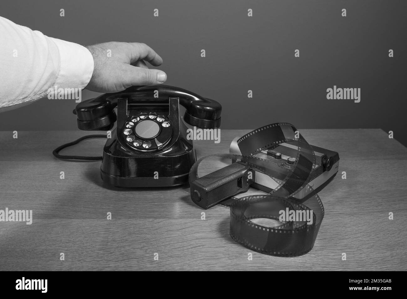 Old movie camera, film, old phone. Male hand takes the phone. Retro ...