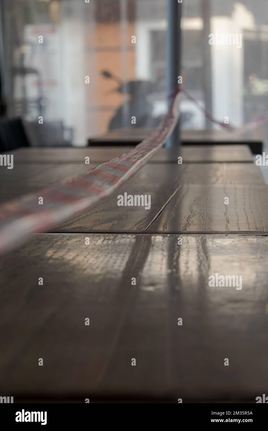 Stacked table seats outside a closed shop. Red prohibition ribbon, due ...