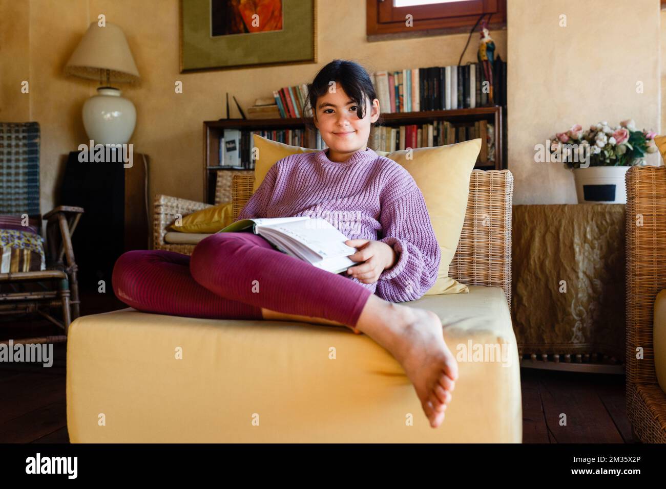 similing girl in lilac pullover reading a book in yellow armchair Stock ...