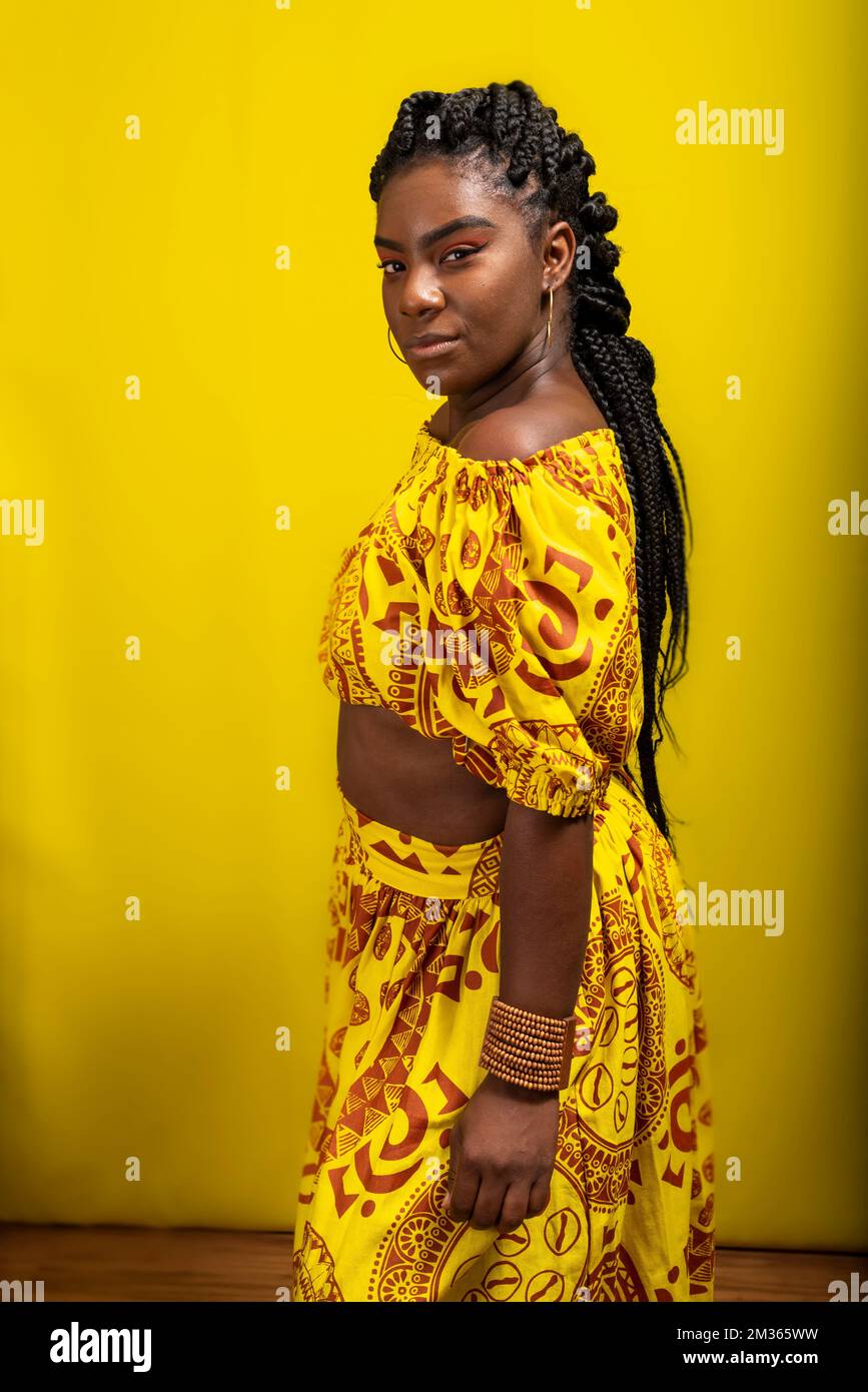 Young woman wearing colorful long clothes over yellow background ...