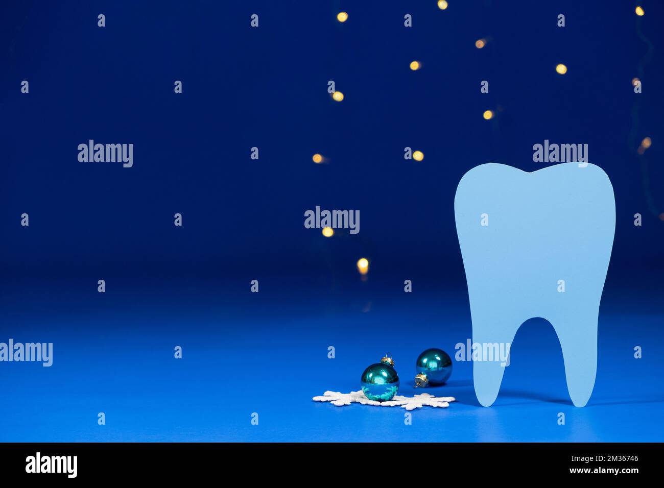 Christmas dentistry - a tooth on a blue background with balls and bokeh ...