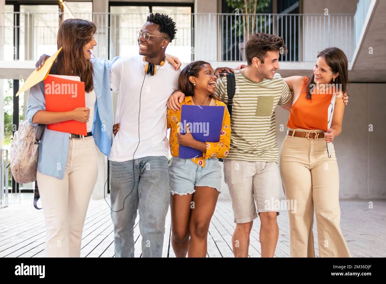 Cheerful students walking together in the campus. Group of international students laughing ...