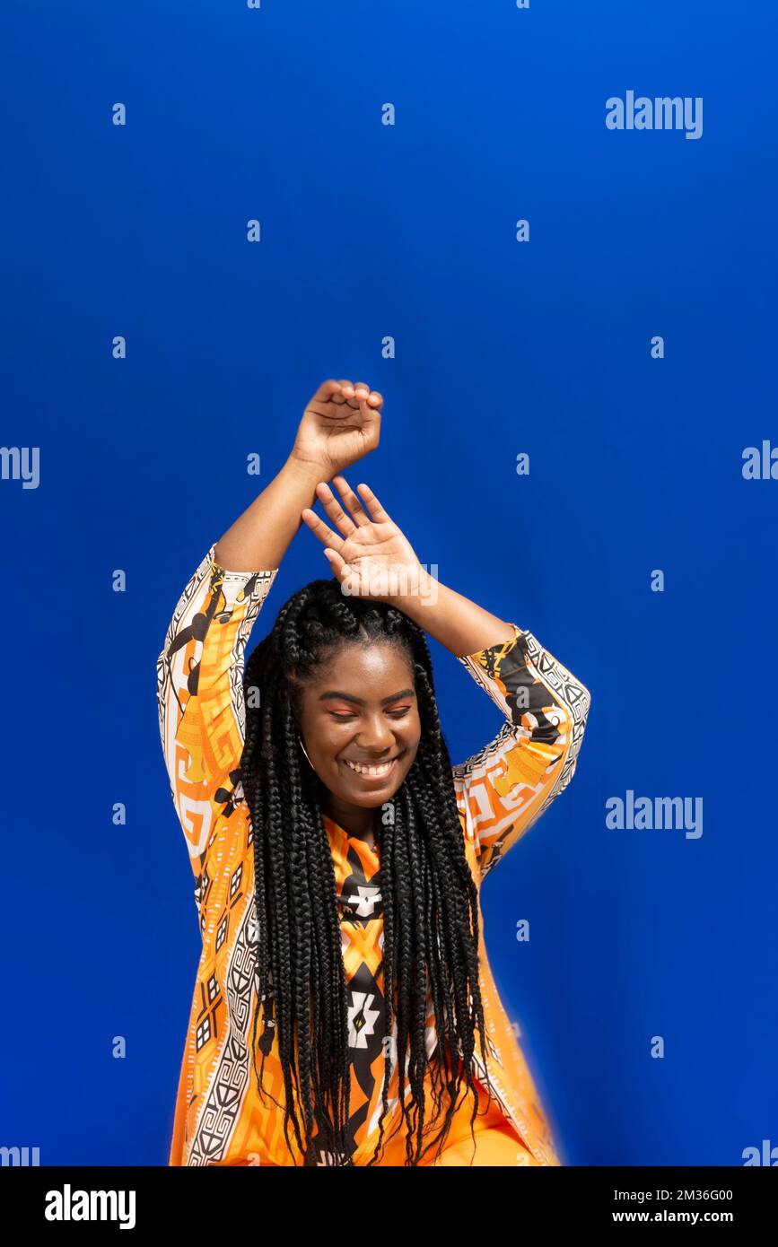 Portrait of young beautiful woman with arms up. isolated against blue ...