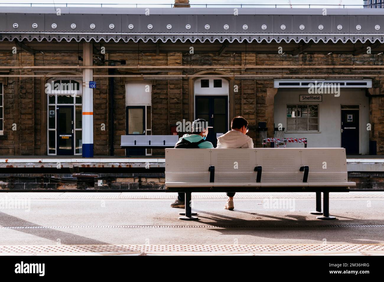 Two people sitting on a bench waiting for the train. Sheffield Train Station. Sheffield, South ...