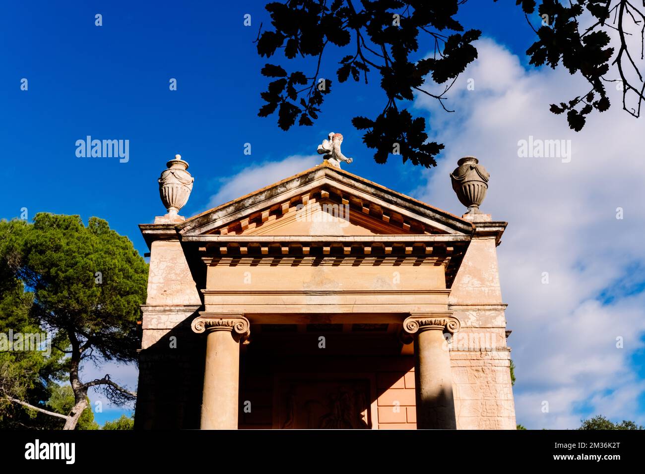 A portico with columns and a triangular pediment on the Greek-style facade of a temple Stock ...