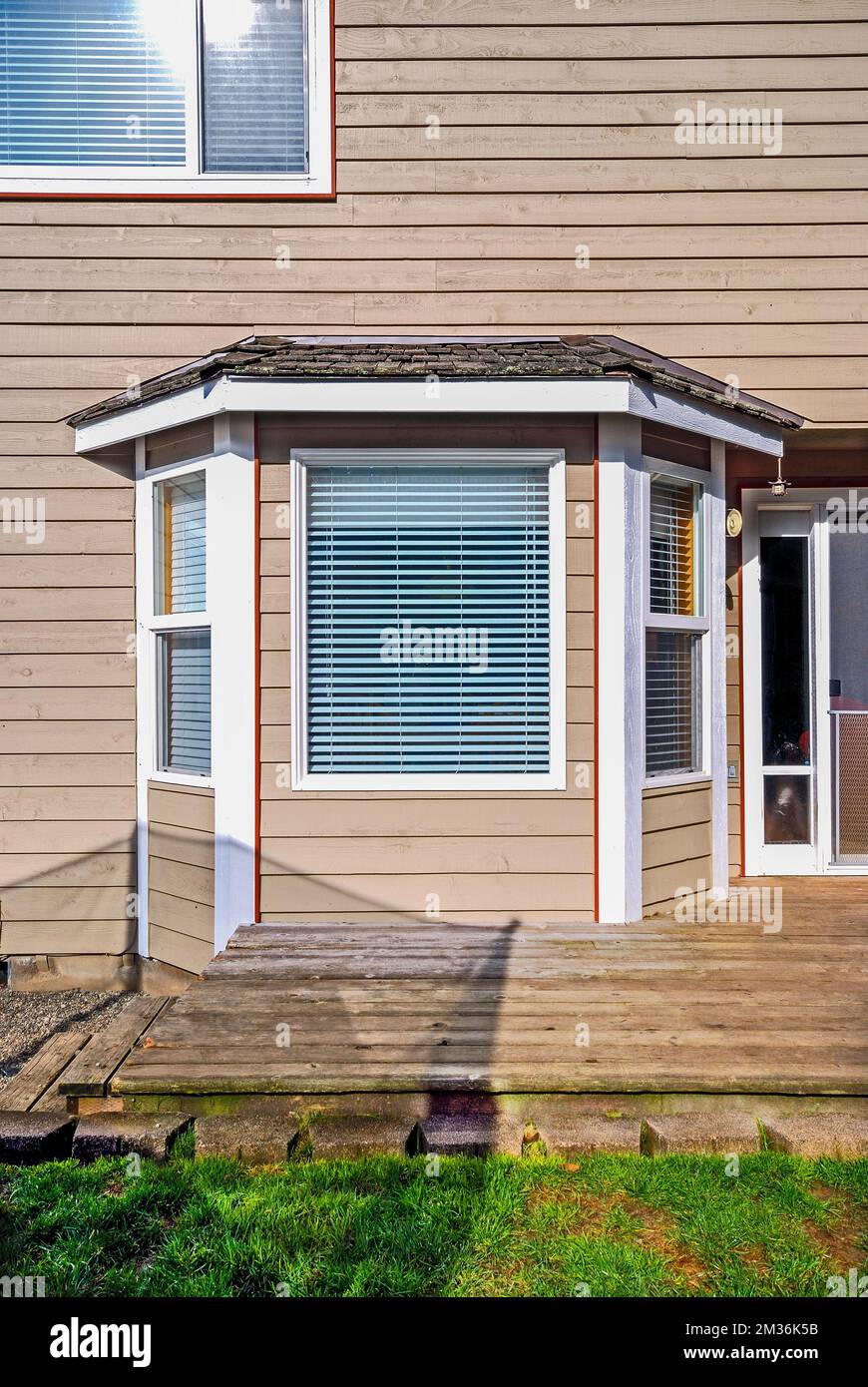 A Suburban Backyard showing a bay window, wooden deck, and the shadow ...