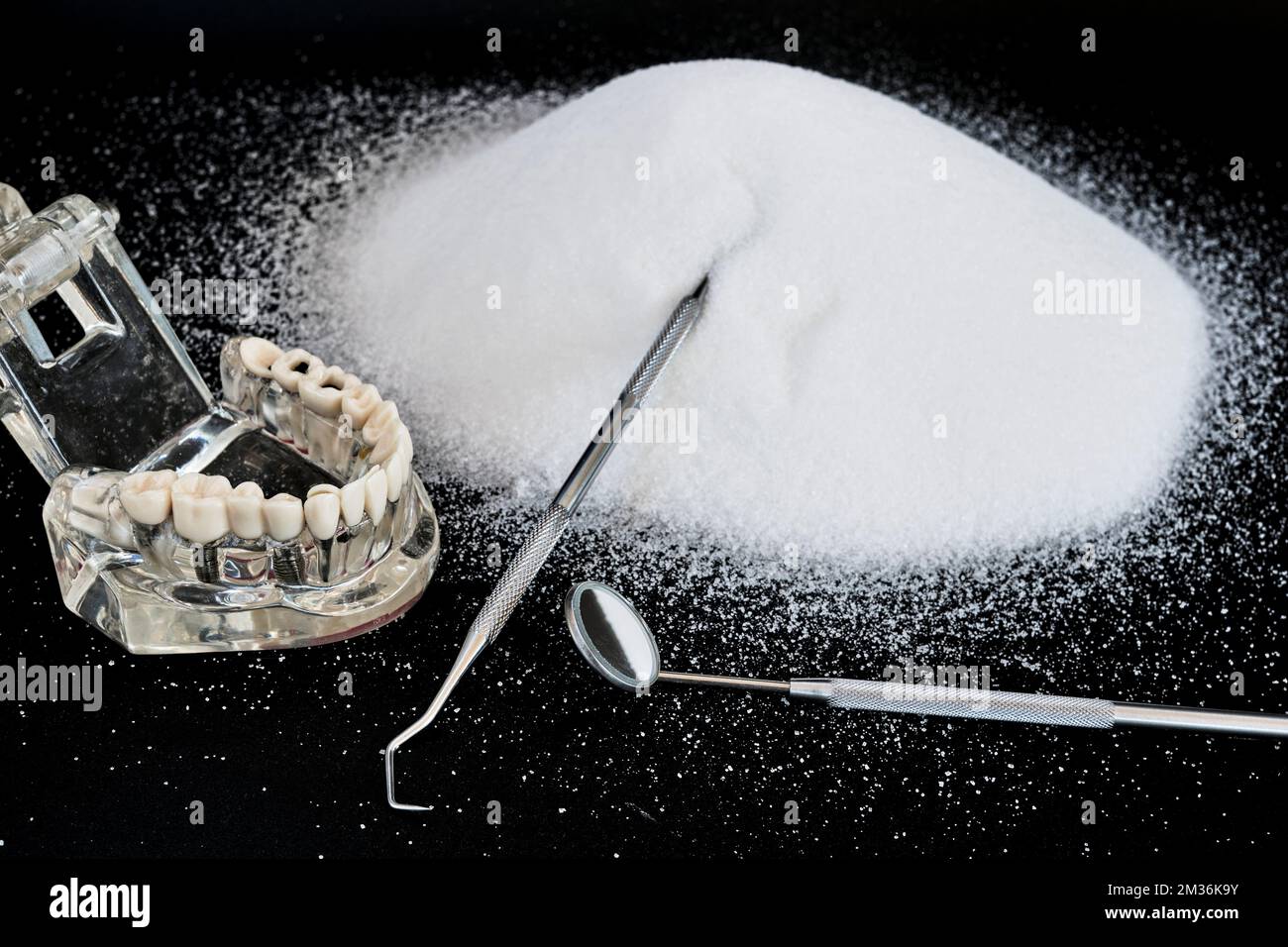 Carious false teeth on pile of sugar on black background Stock Photo ...