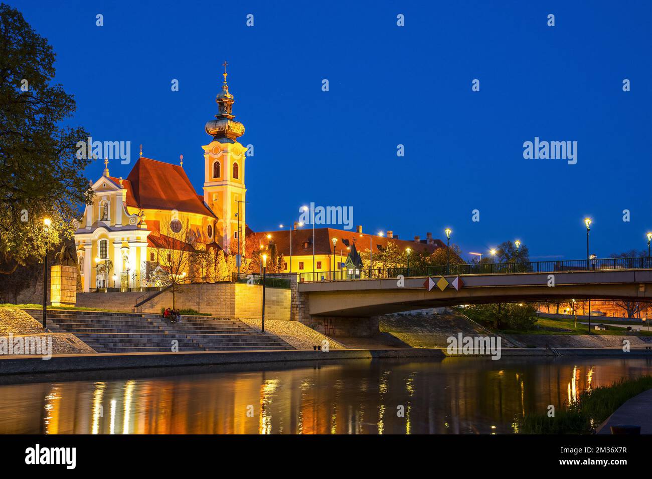 Gyor, city in Hungary, baroque Carmelite church by night reflecting in ...