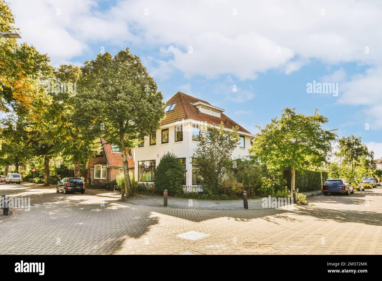 an empty street with cars parked on the side and trees lining the road ...