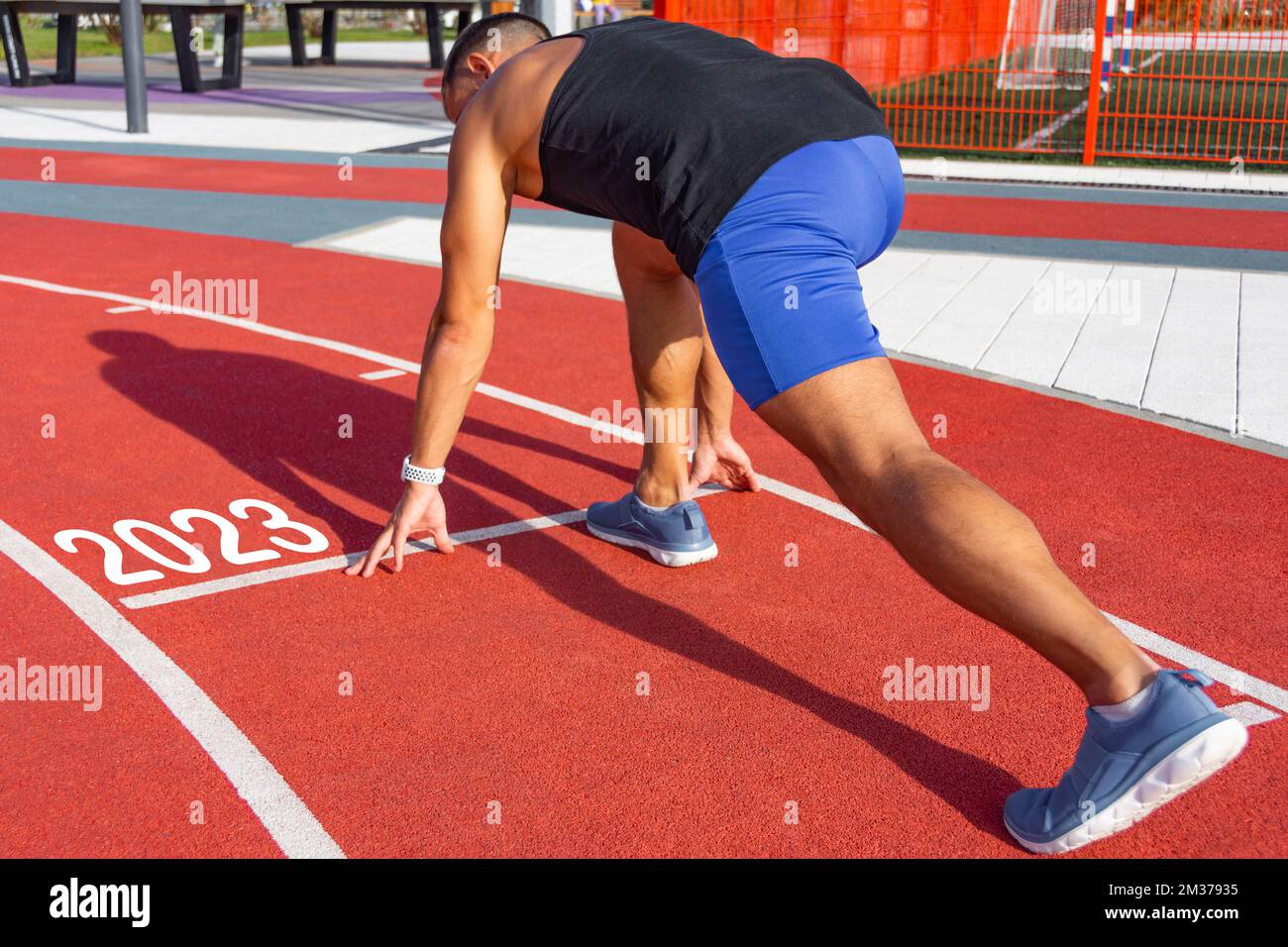 Athlete runner in a pose ready to start on a red treadmill line with ...