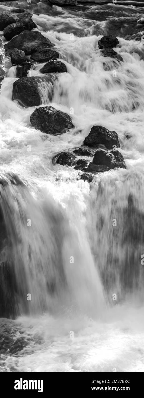 A vertical black-and-white shot of a small waterfall in Yellowstone ...