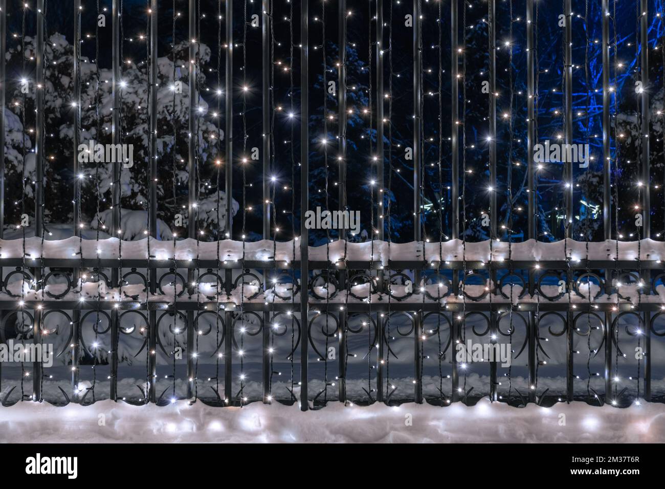 Ornamental, metal fence decorated with led illumination. Snow covering ...