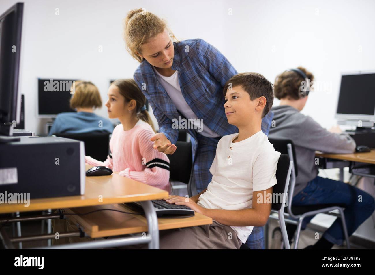 Teacher helping student with computer work Stock Photo - Alamy