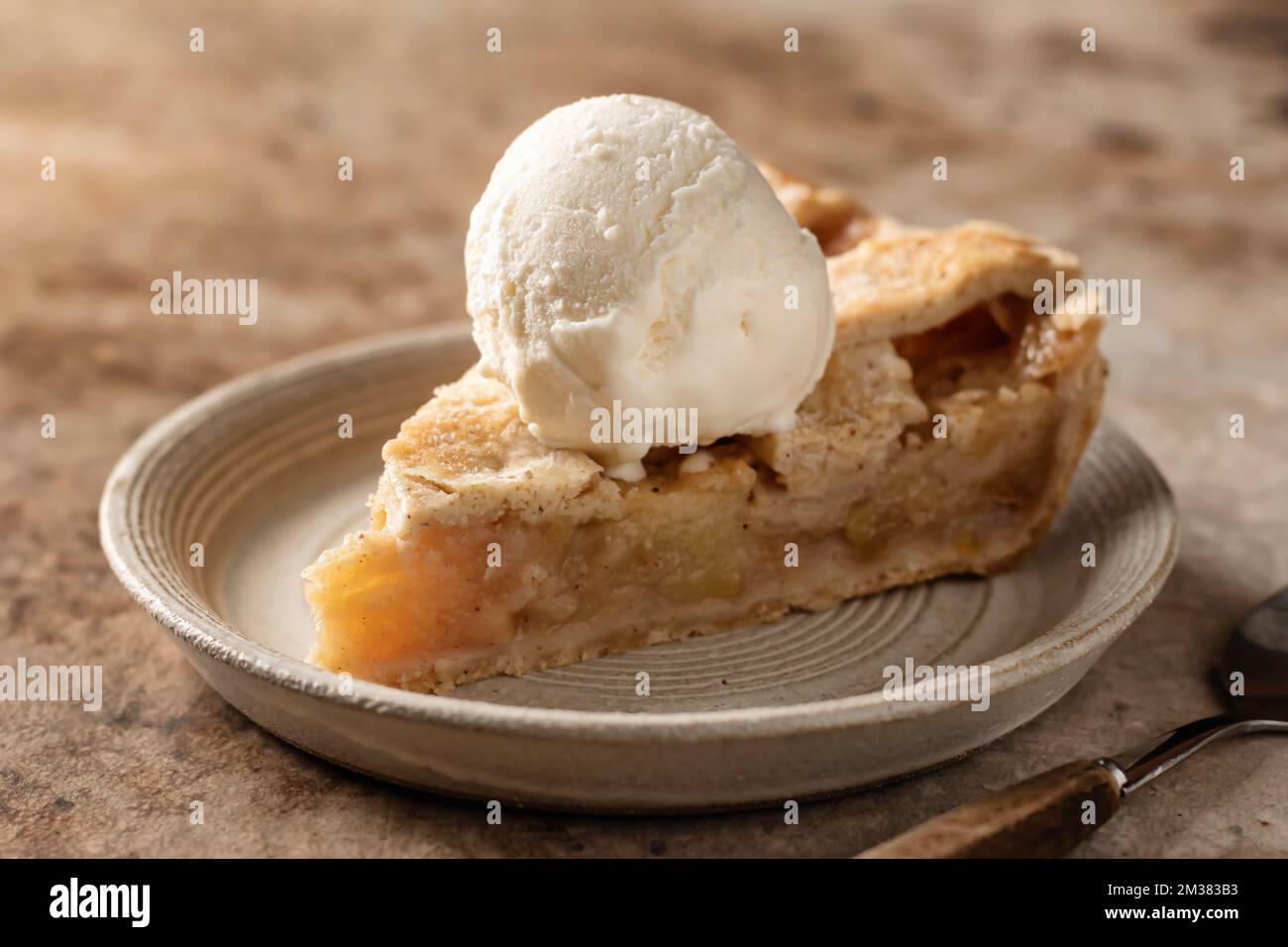 Piece of traditional apple pie with ice cream on brown textured ...