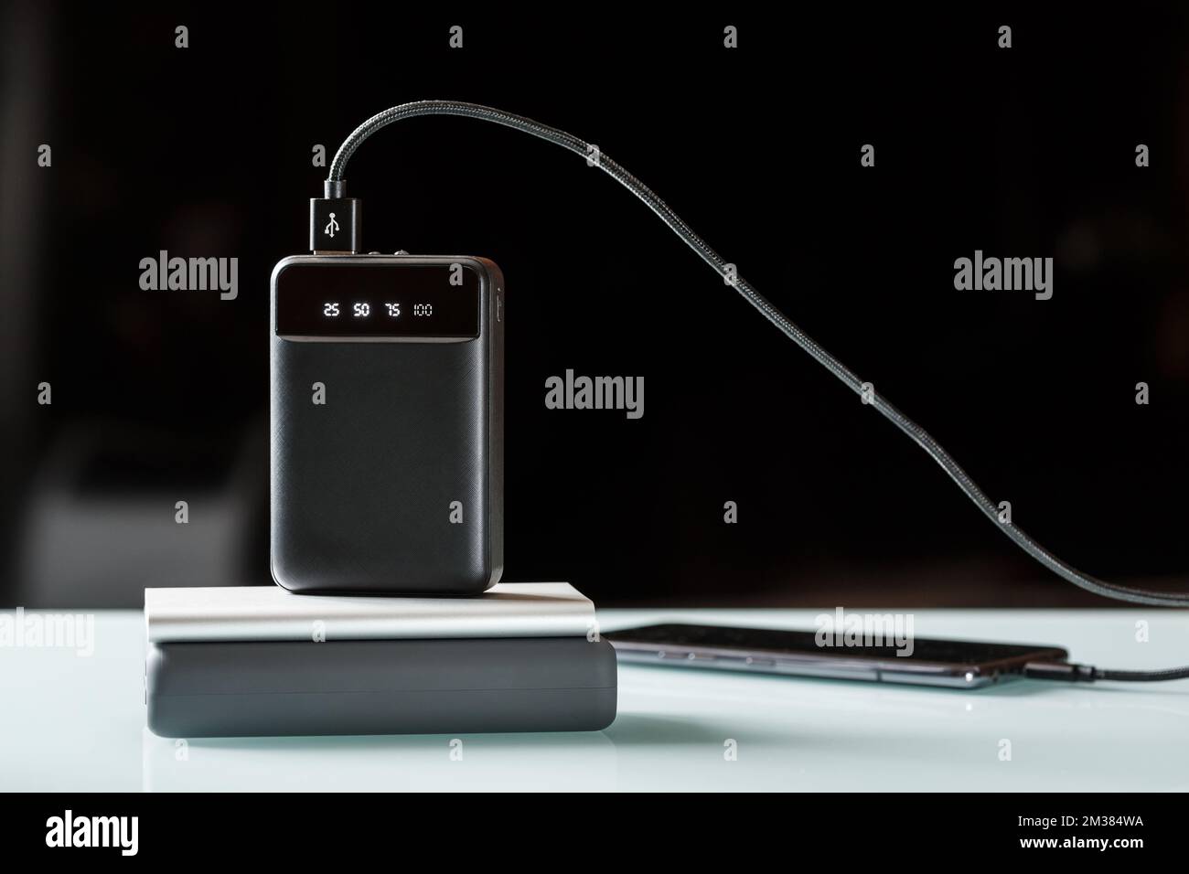 Stack of powerbanks with a black powerbank and black cord charging ...