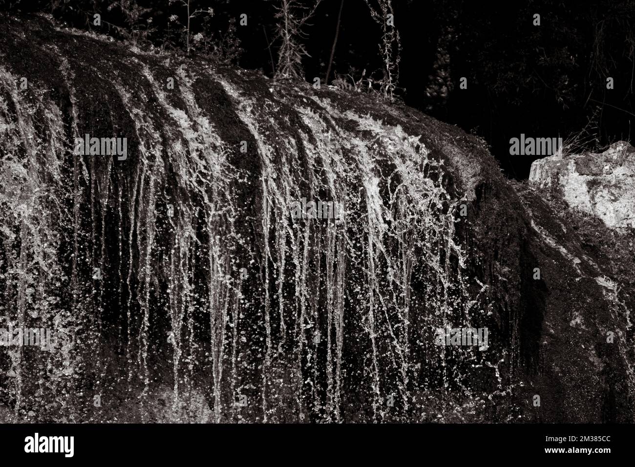 A grayscale shot of a small waterfall in a forest Stock Photo - Alamy