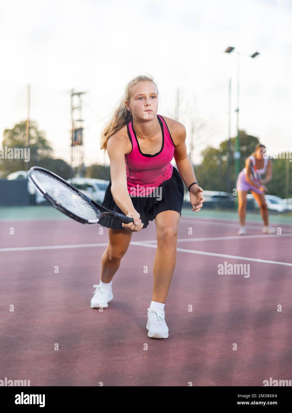 Sporty teenage girl tennis player playing tennis at court. View through ...