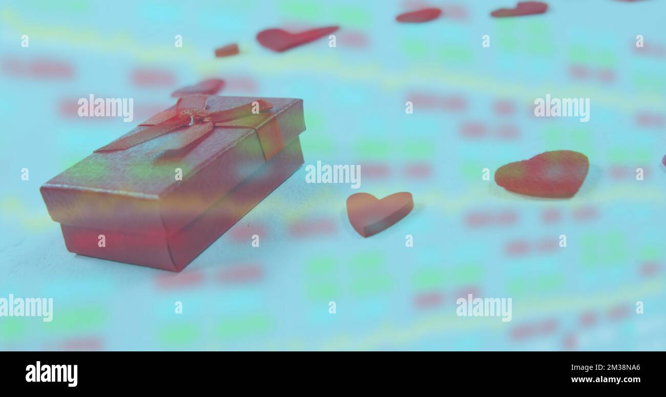 Image of gift box and heart shapes over moving graphs and trading board ...