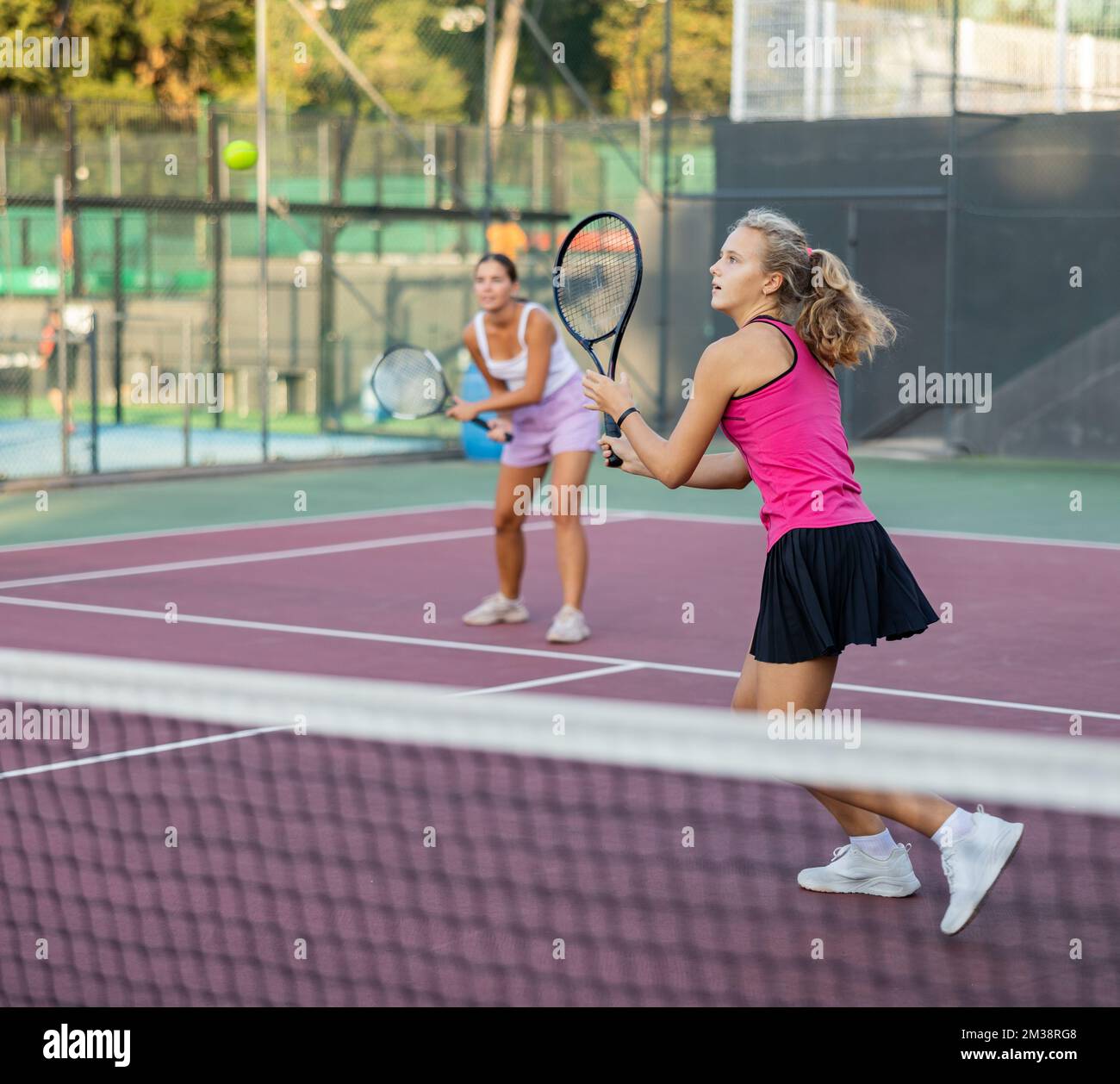 Young woman and her female partner playing tennis on court during ...