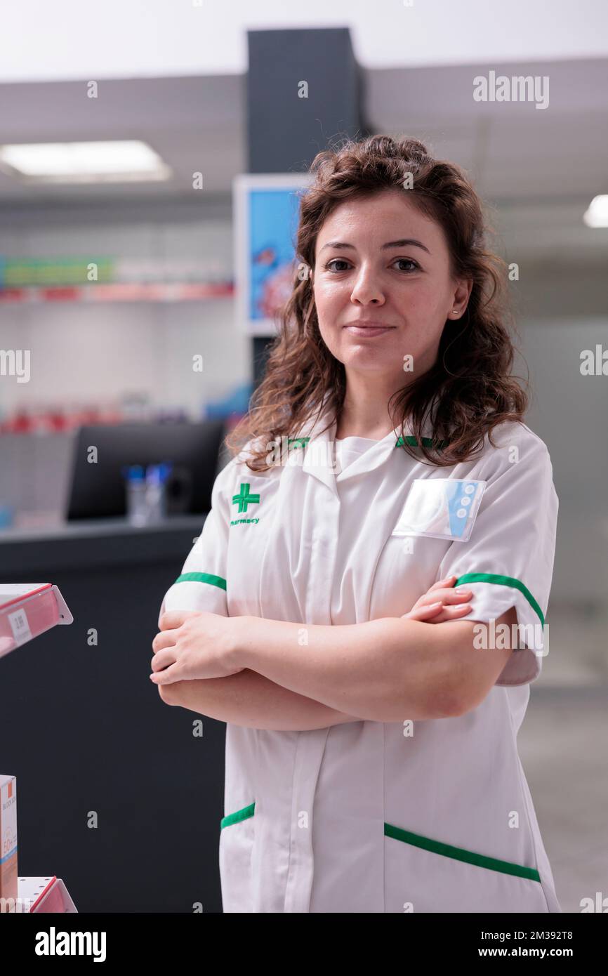 Pharmacy worker in medical uniform standing with arm crossed in ...