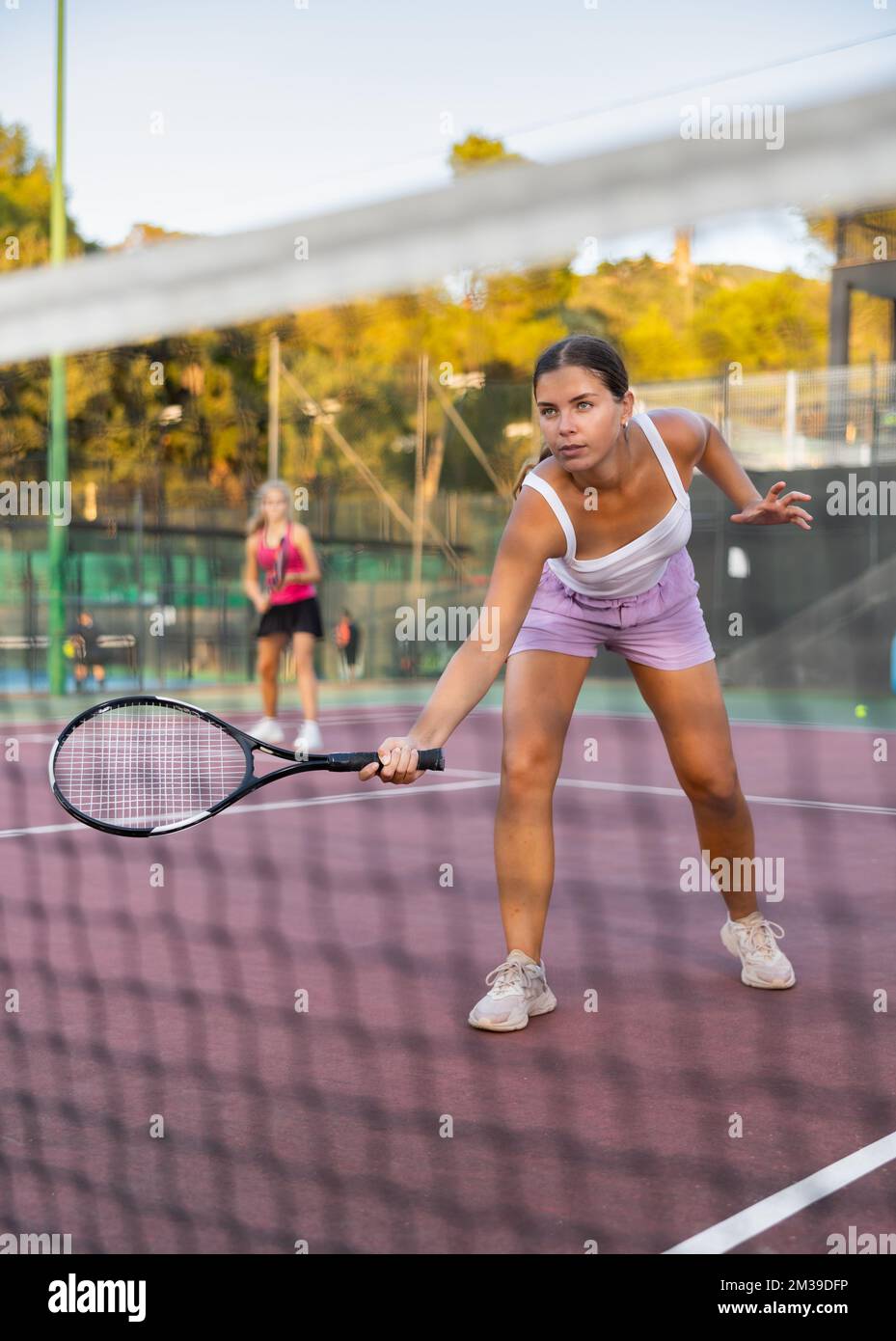 Sporty teenage girl tennis player playing tennis at court. View through ...