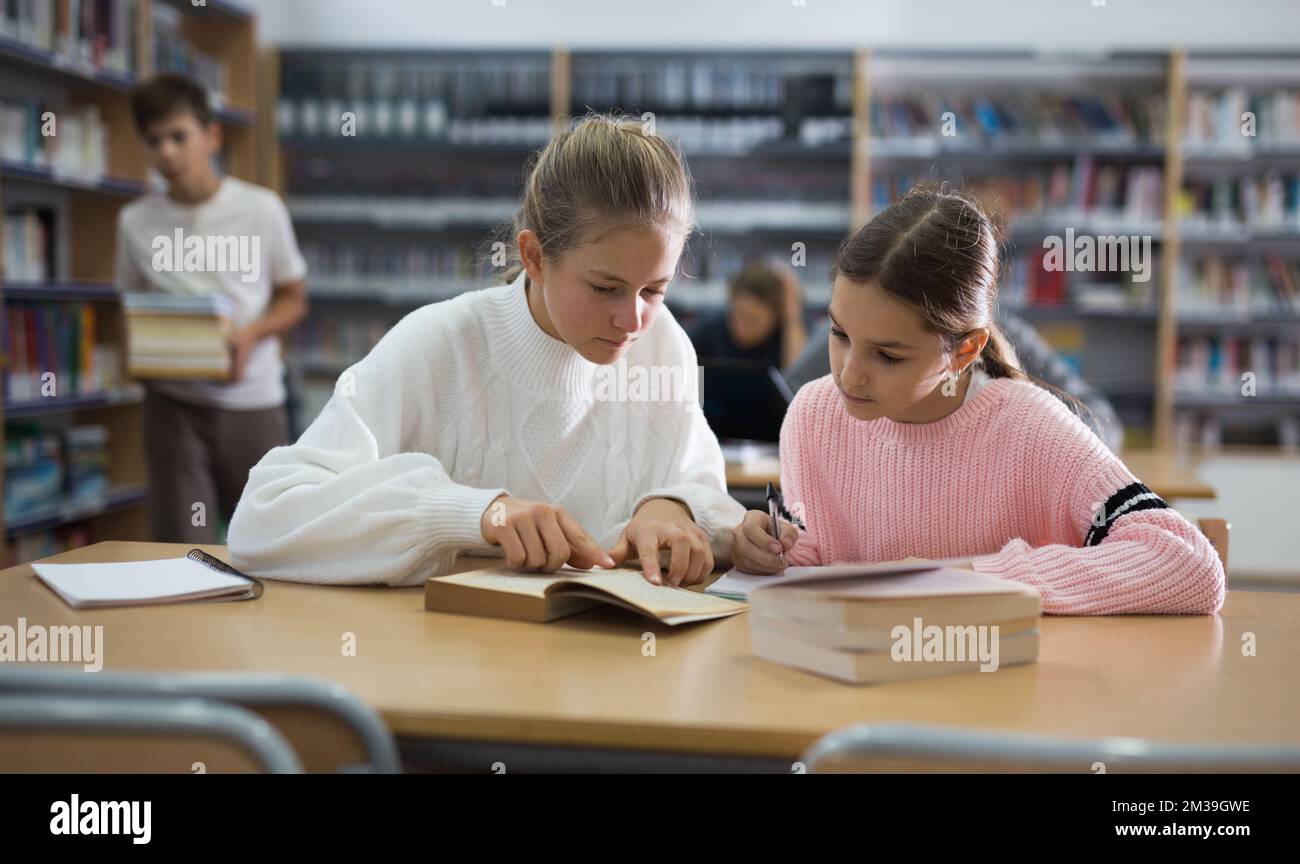 Girls doing homework together in library Stock Photo - Alamy