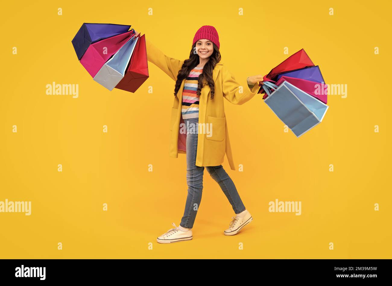 Funny teen girl hold shopping bag enjoying sale isolated on yellow ...