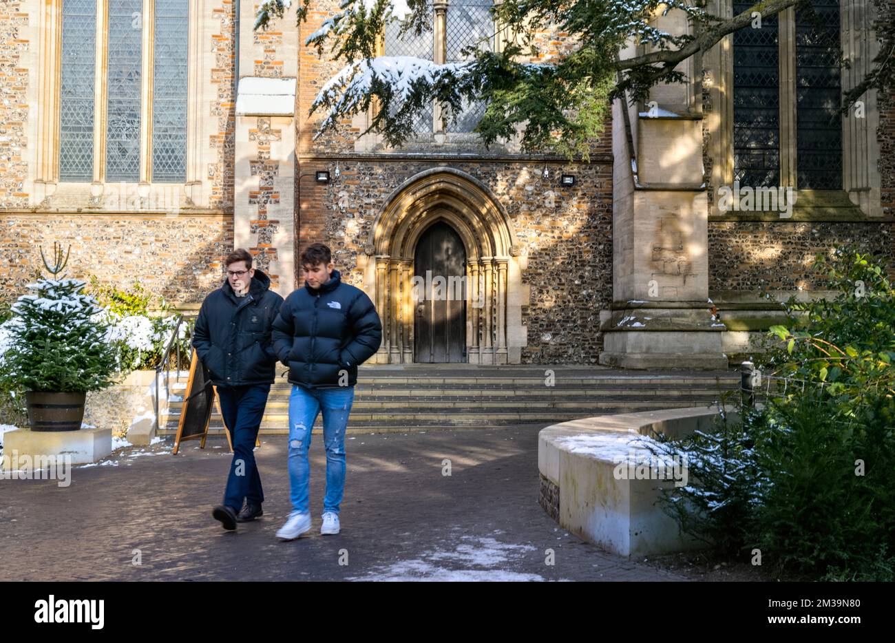 Two people walking in the grounds of St. Albans Cathedral also known as ...