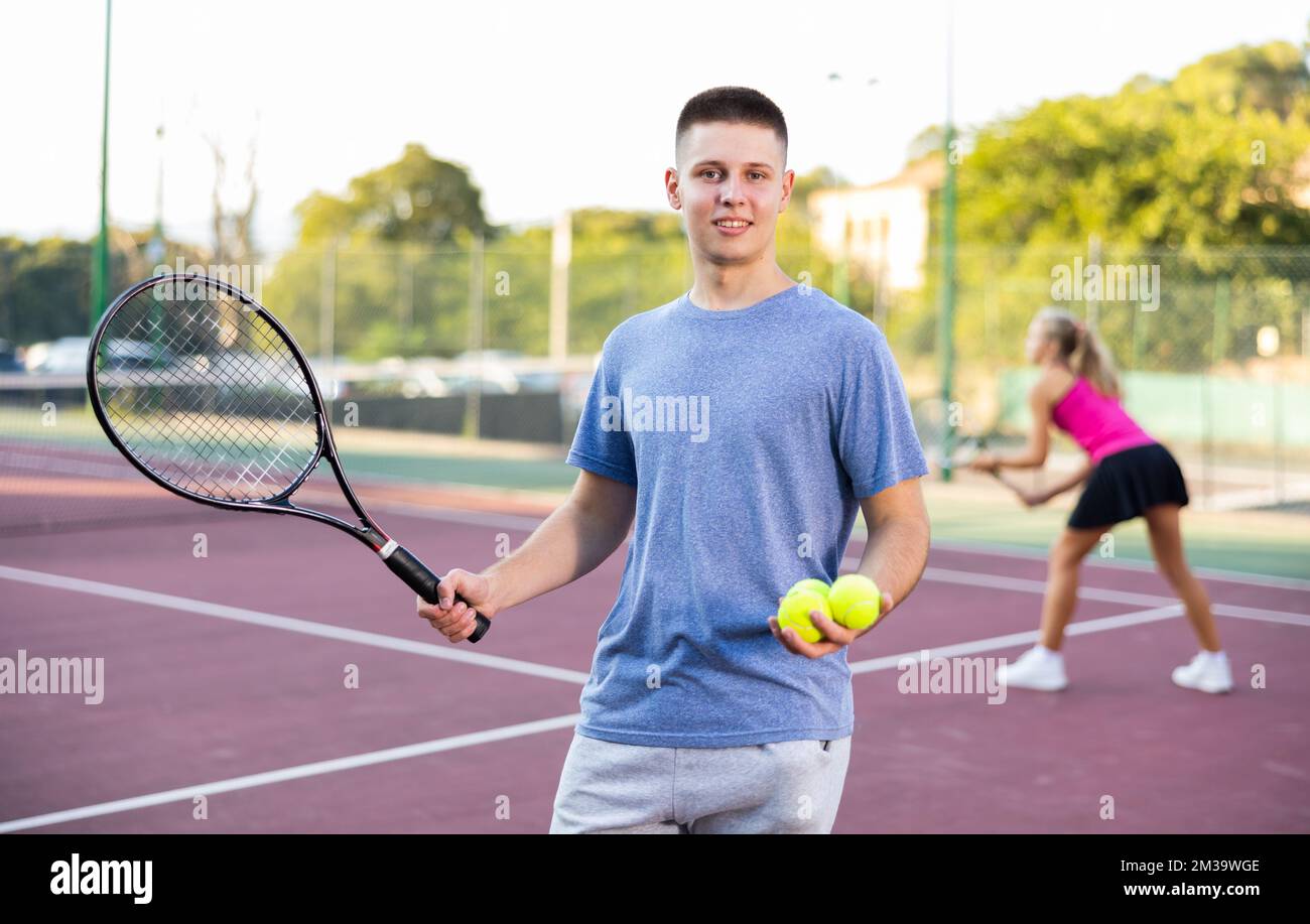 Portrait of positive young man with racket and ball in his hands on ...