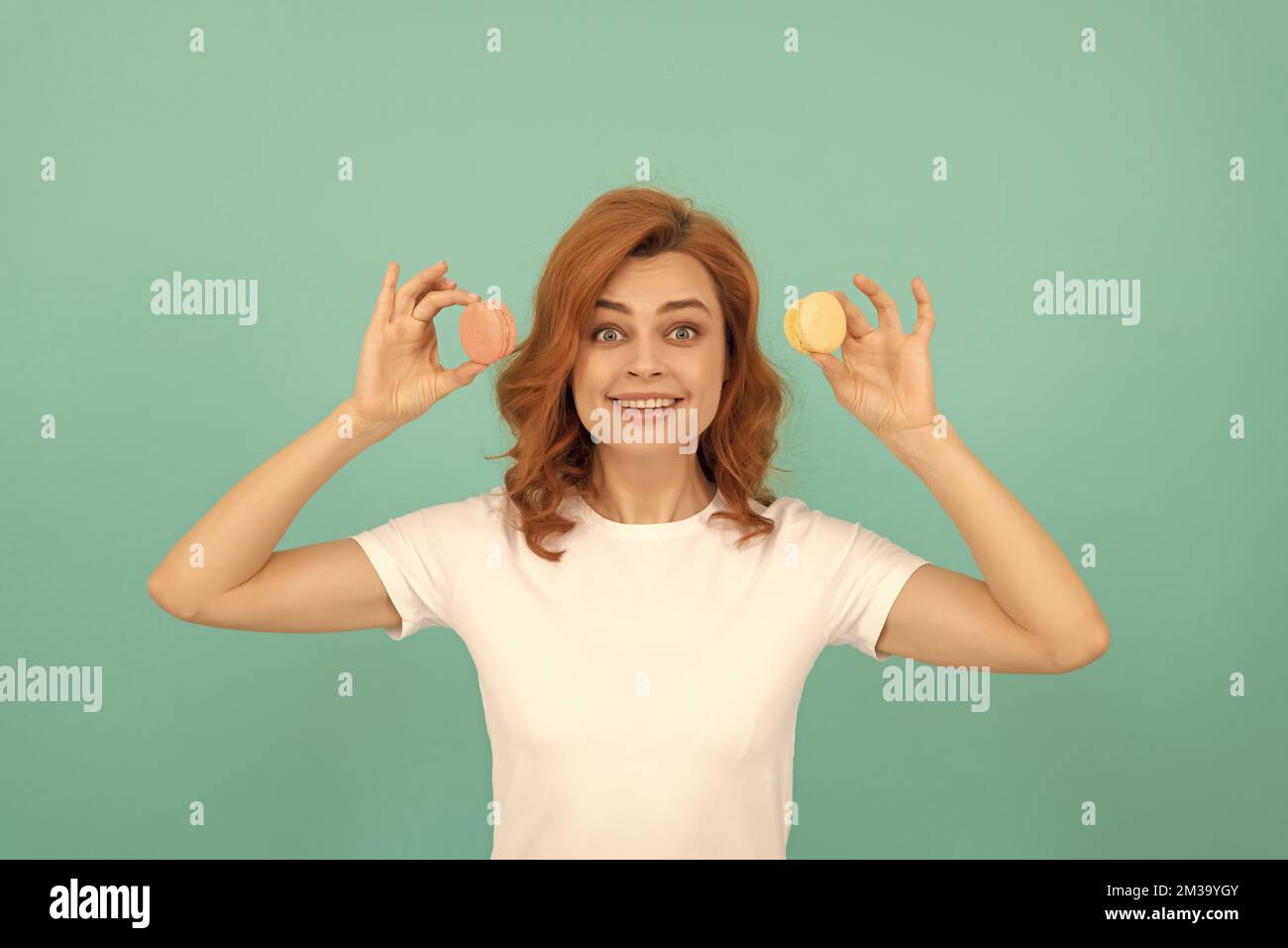 surprised lady hold sweet macaron french cookie on blue background ...