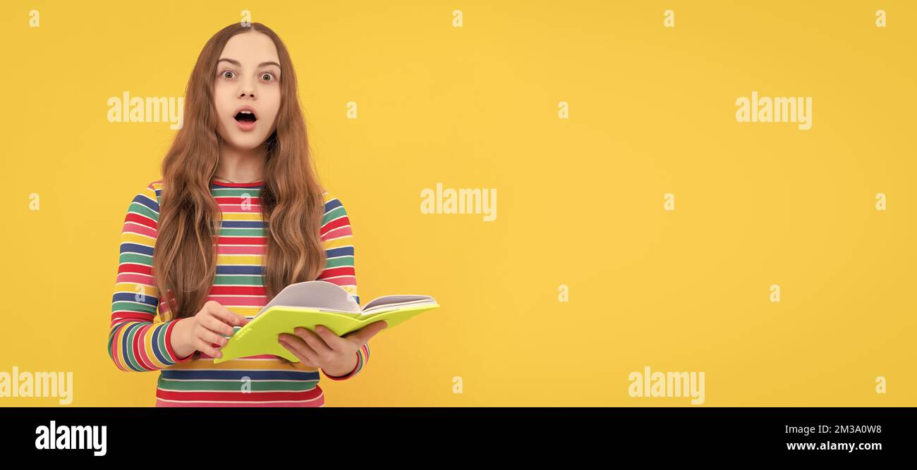 Surprised open-eyed kid hold school book yellow background, surprise ...