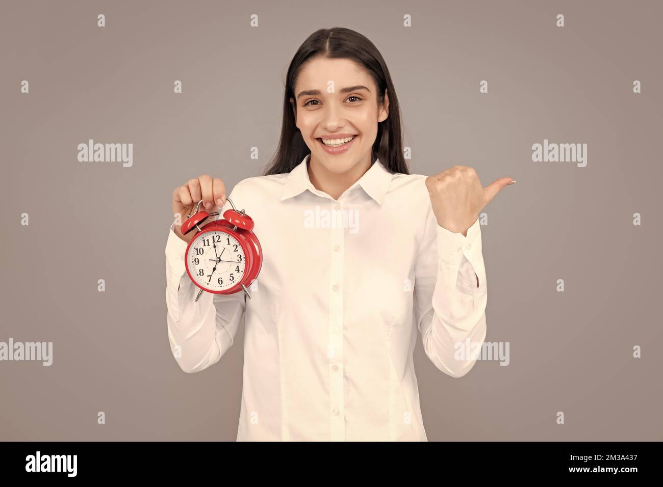 Funny girl hold alarm clock isolated on gray background Stock Photo - Alamy