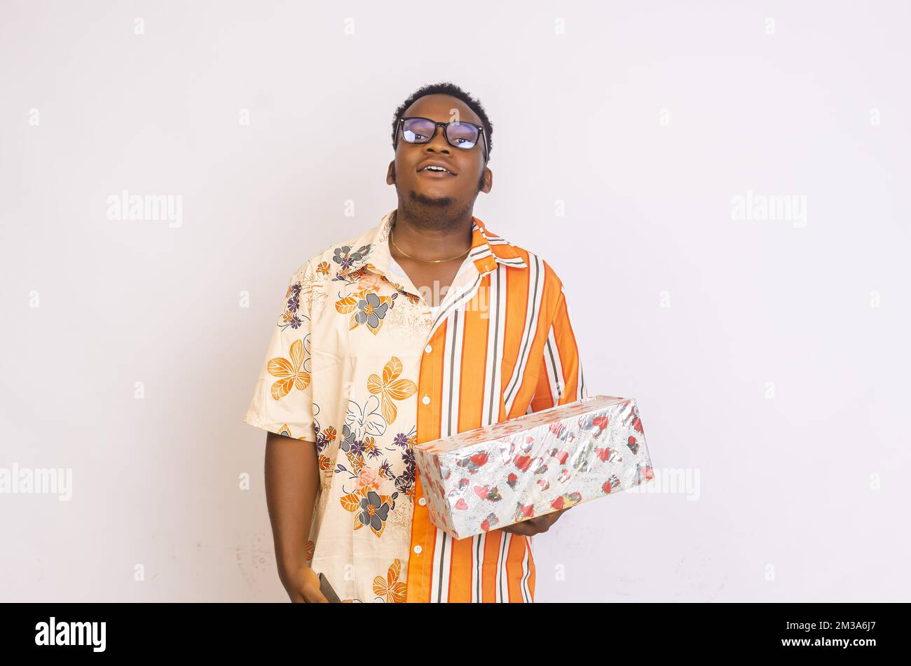 Young African male wearing glasses holding a gift box in his hands and ...