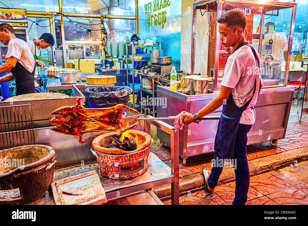 BANGKOK, THAILAND - APRIL 23, 2019: The young cook roasting peking duck ...