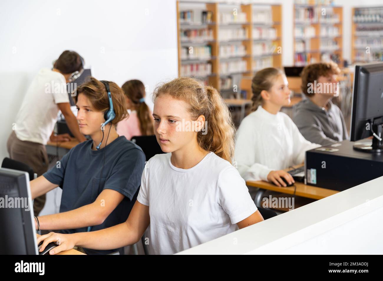Group of teenage boys and girls learning to use computers in classroom ...
