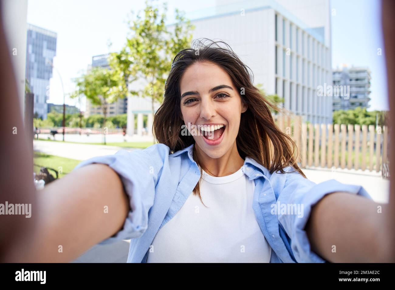 Young smiling woman Taking selfie photo at university campus. Cheerful student posing outdoors ...