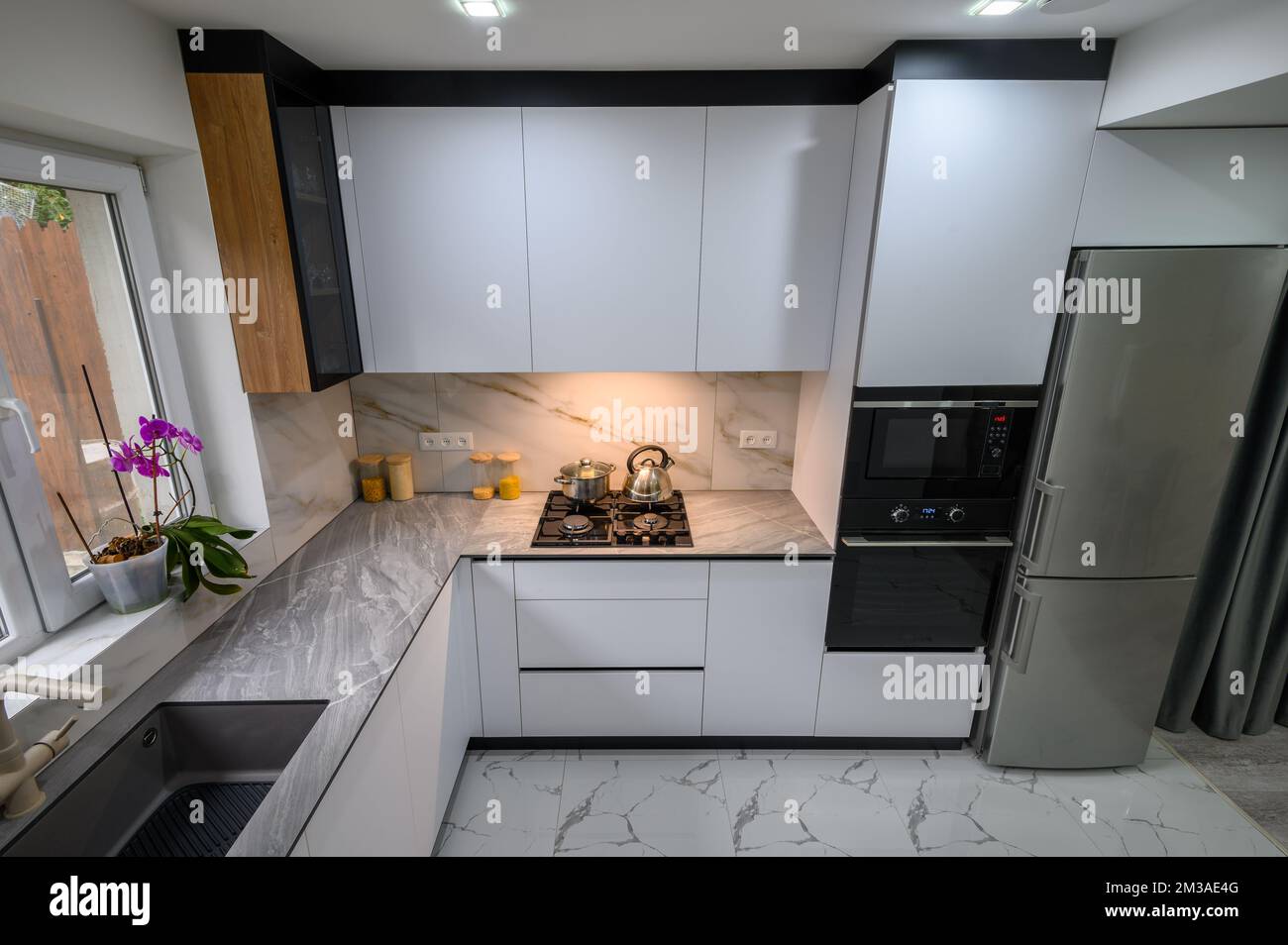 A spacious and updated kitchen with a white color scheme and marble ...