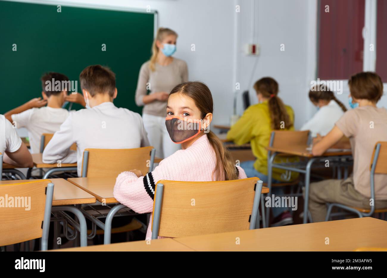 Girl in mask turned around and looking at camera during lesson in ...