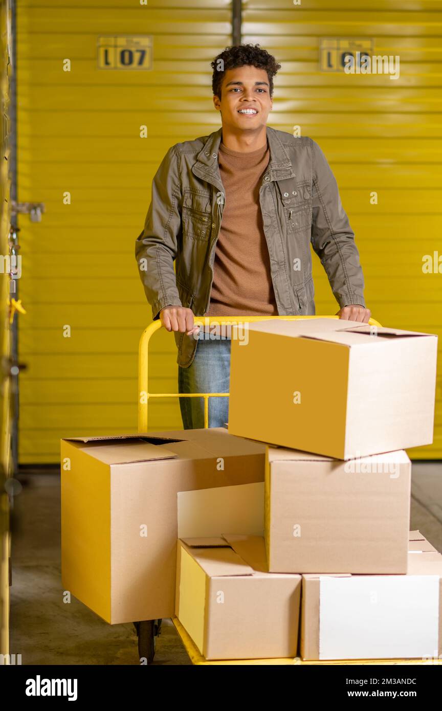 Young smiling man working in a warehouse and distributing boxes Stock ...