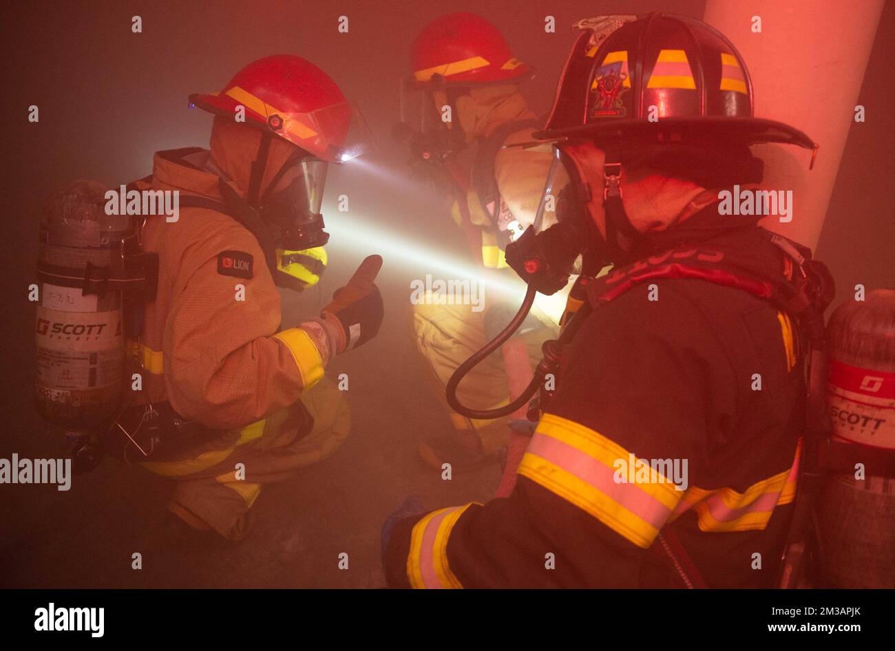 U.S. Navy Sailors and a local firefighter participate in a fire drill ...