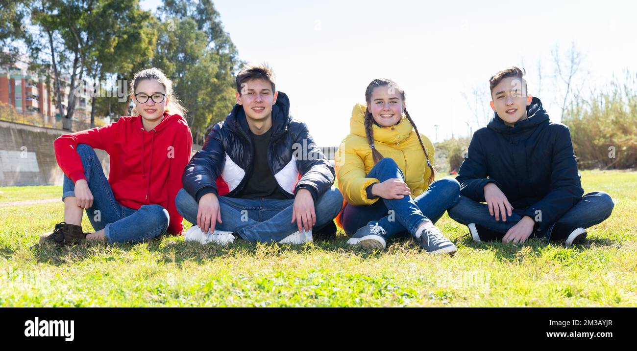 Happy teenagers sitting on green lawn Stock Photo - Alamy
