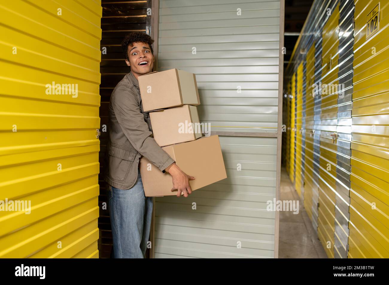 Young man carrying many heavy boxes Stock Photo - Alamy