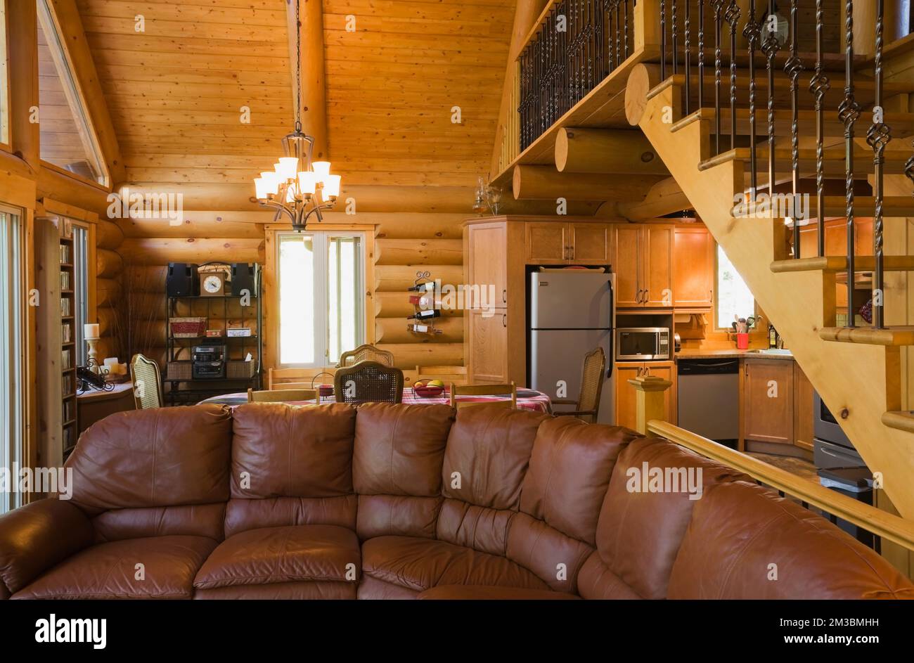 Living room with dark tan leather sofa, kitchen room and pine wood ...