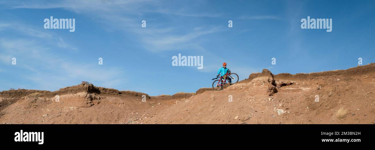 male cyclist is riding a gravel bike on cliff edge in Colorado prairie ...