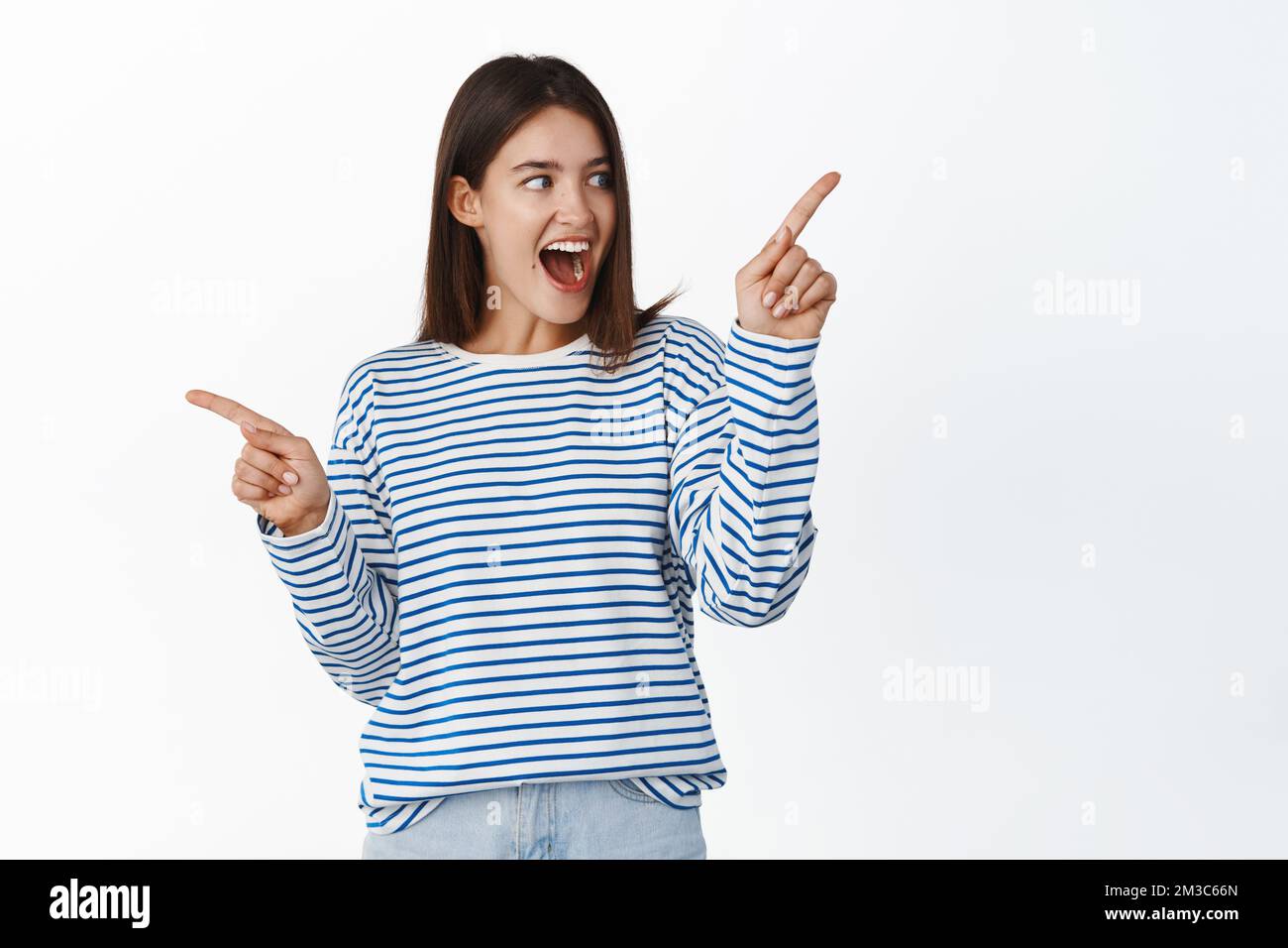 Excited smiling brunette girl pointing sideways, showing two ways ...
