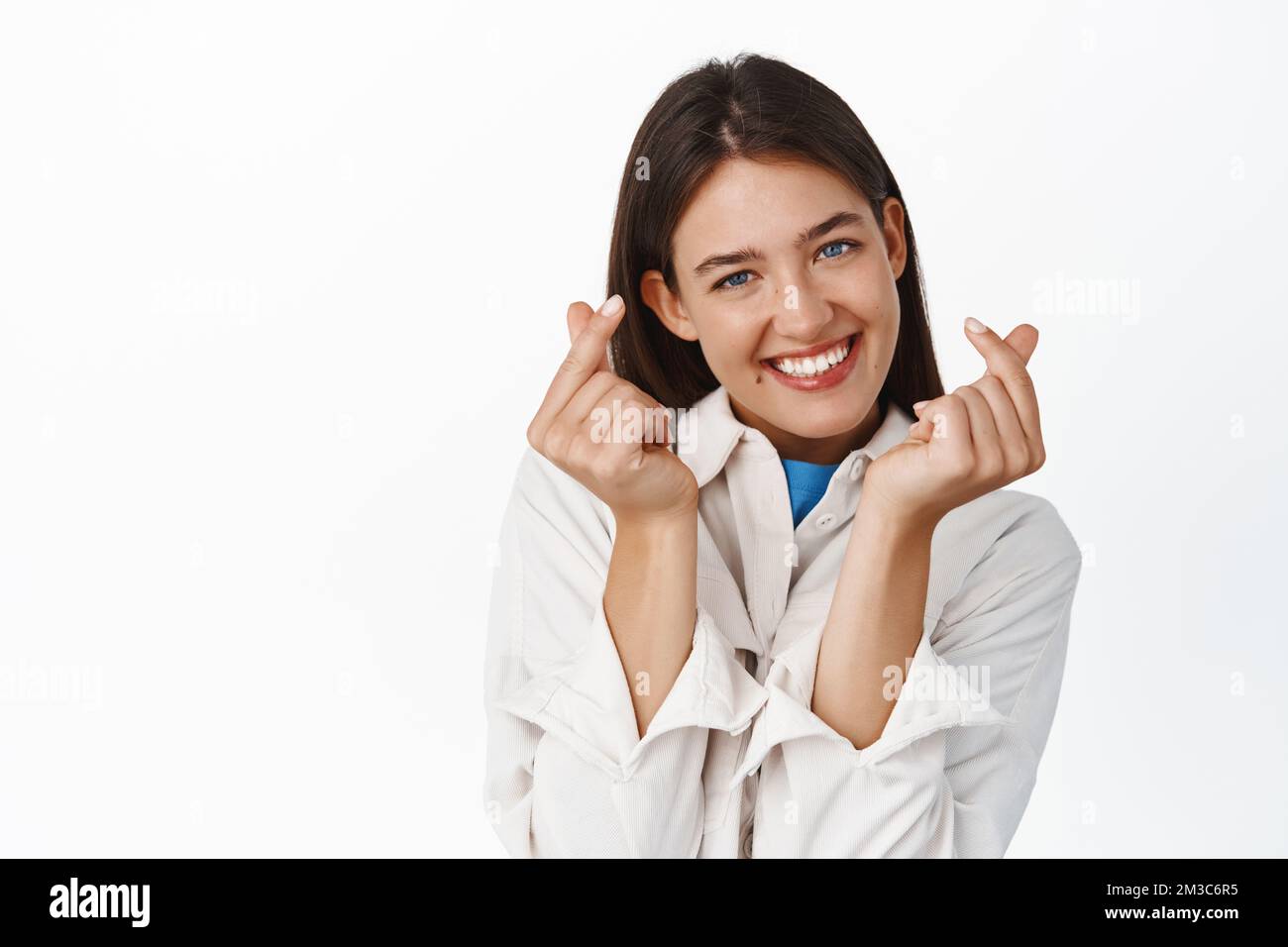 Cute smiling girl showing hand hearts and looking romantic at camera ...