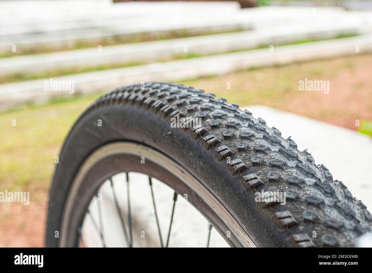 Close up to a black bike tire pattern and blurred green garden at ...